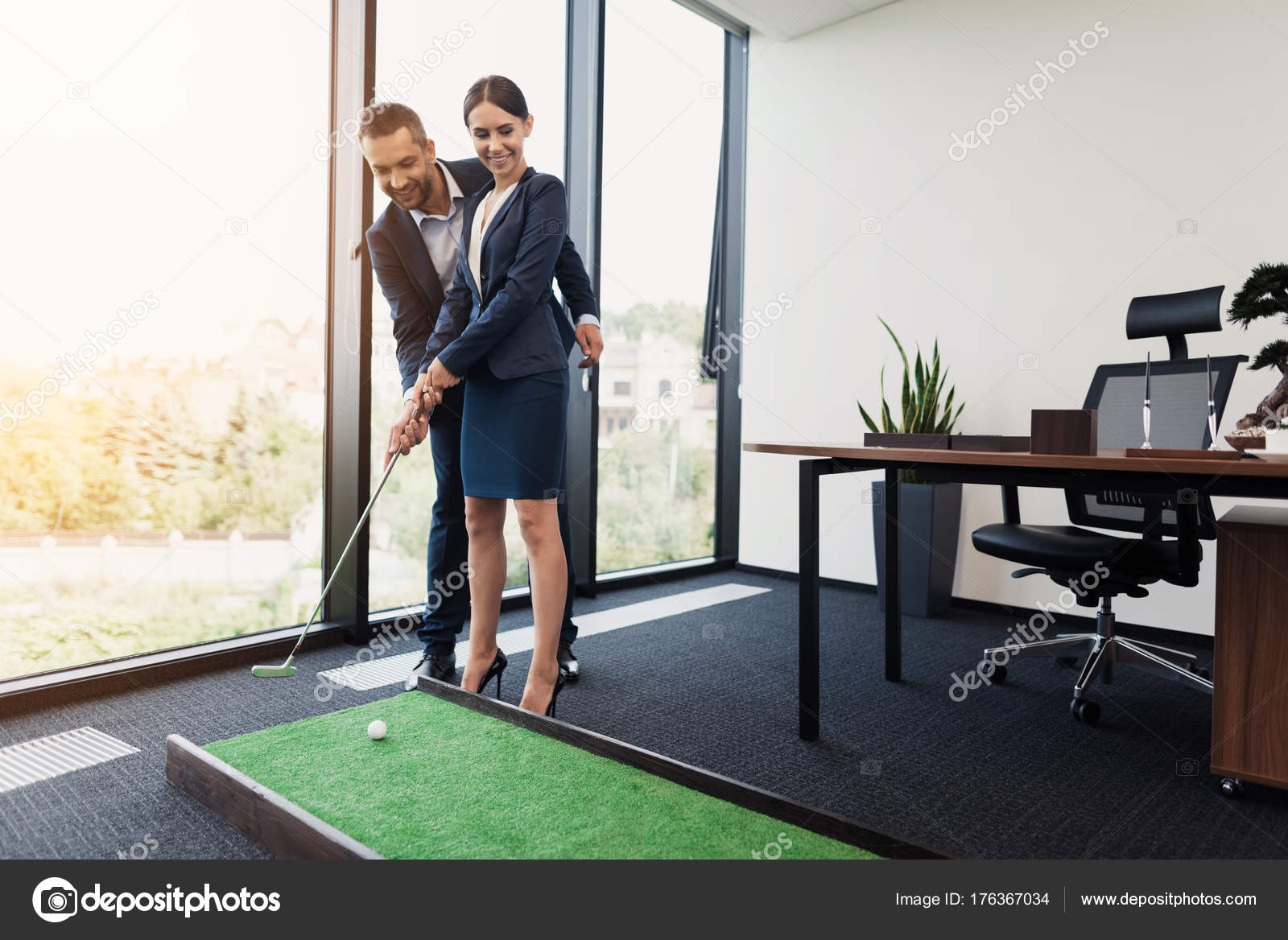 An elderly man is teaching his secretary to play mini golf. He directs ...