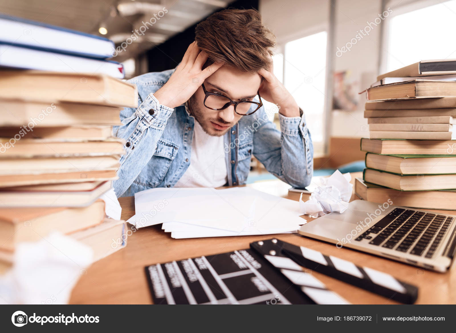 Freelancer man looking at notes frustrated at laptop sitting at desk ...