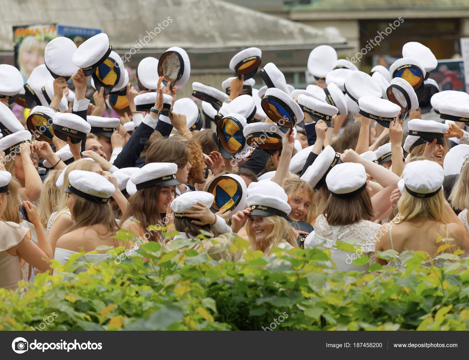 Hands holding many swedish white graduation caps, green trees in ...