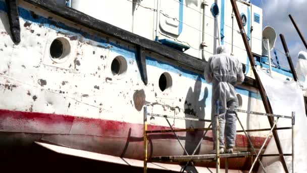Working people tear off paint on metal in repairs process at shipyard ...