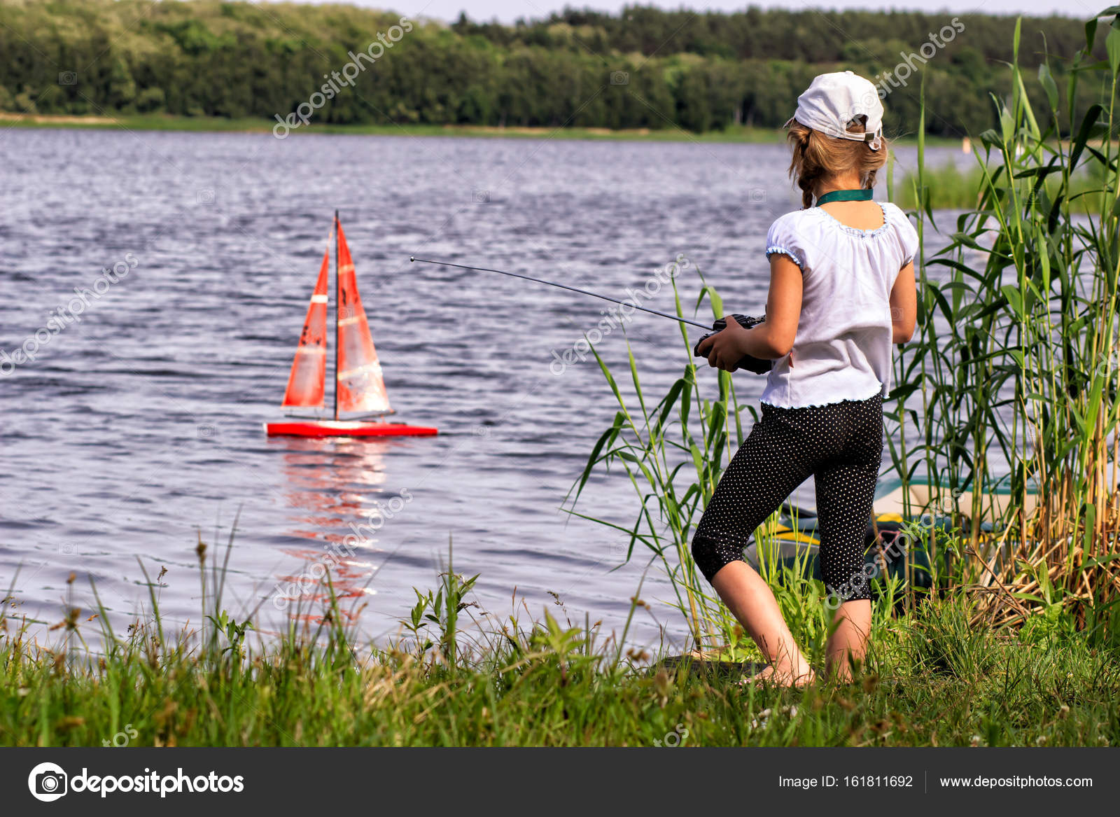 Girl playing with a remote controlled boat. Handmade model sailboat on ...