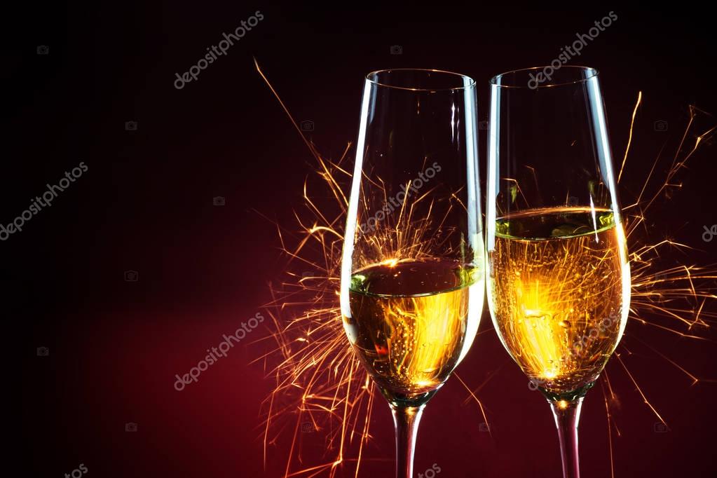 Fiesta de Año Nuevo con dos copas de champán y bengalas, fondo rojo ...