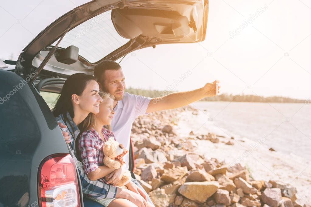 Familia feliz en un viaje por carretera en su coche. Papá, mamá e hija ...