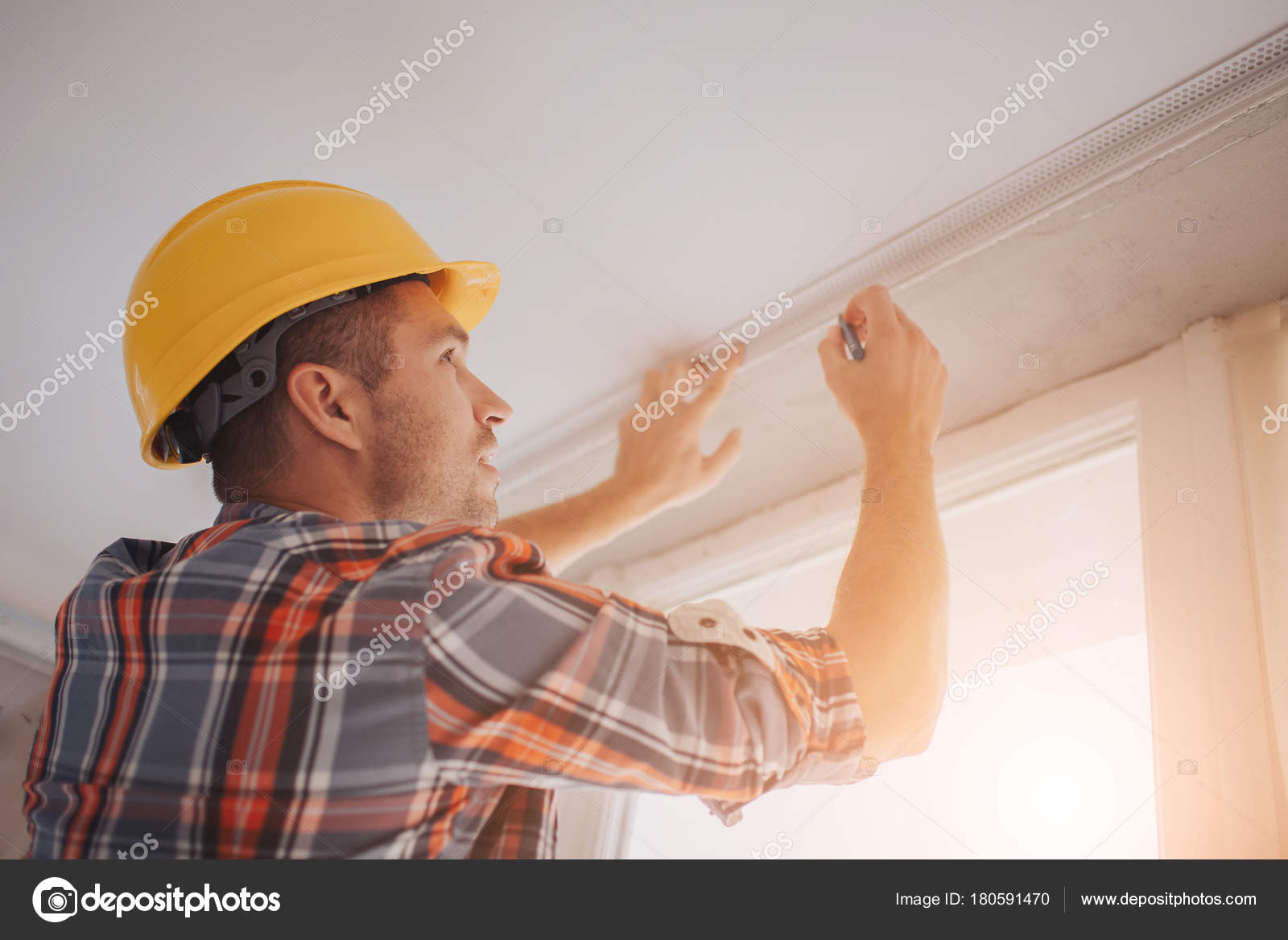 The builder works at the construction site and measures the ceiling ...