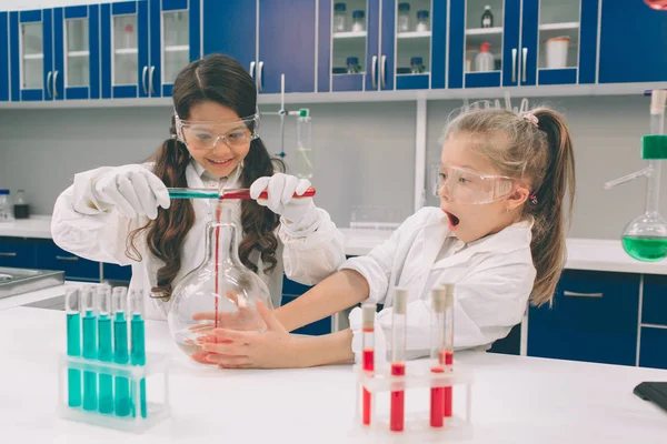 Two little kids in lab coat learning chemistry in school laboratory ...