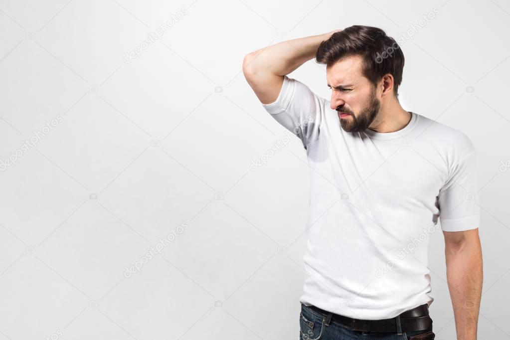 Una foto del guapo está olfateando su axila. Hay un gran punto de sudor ...