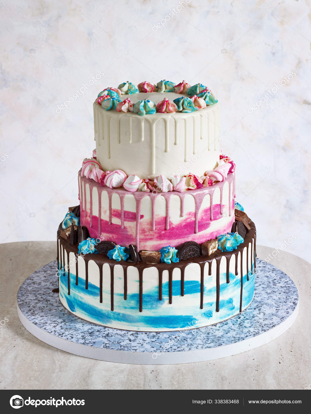 Three-tiered colored cake with colored smudges of chocolate on a light ...