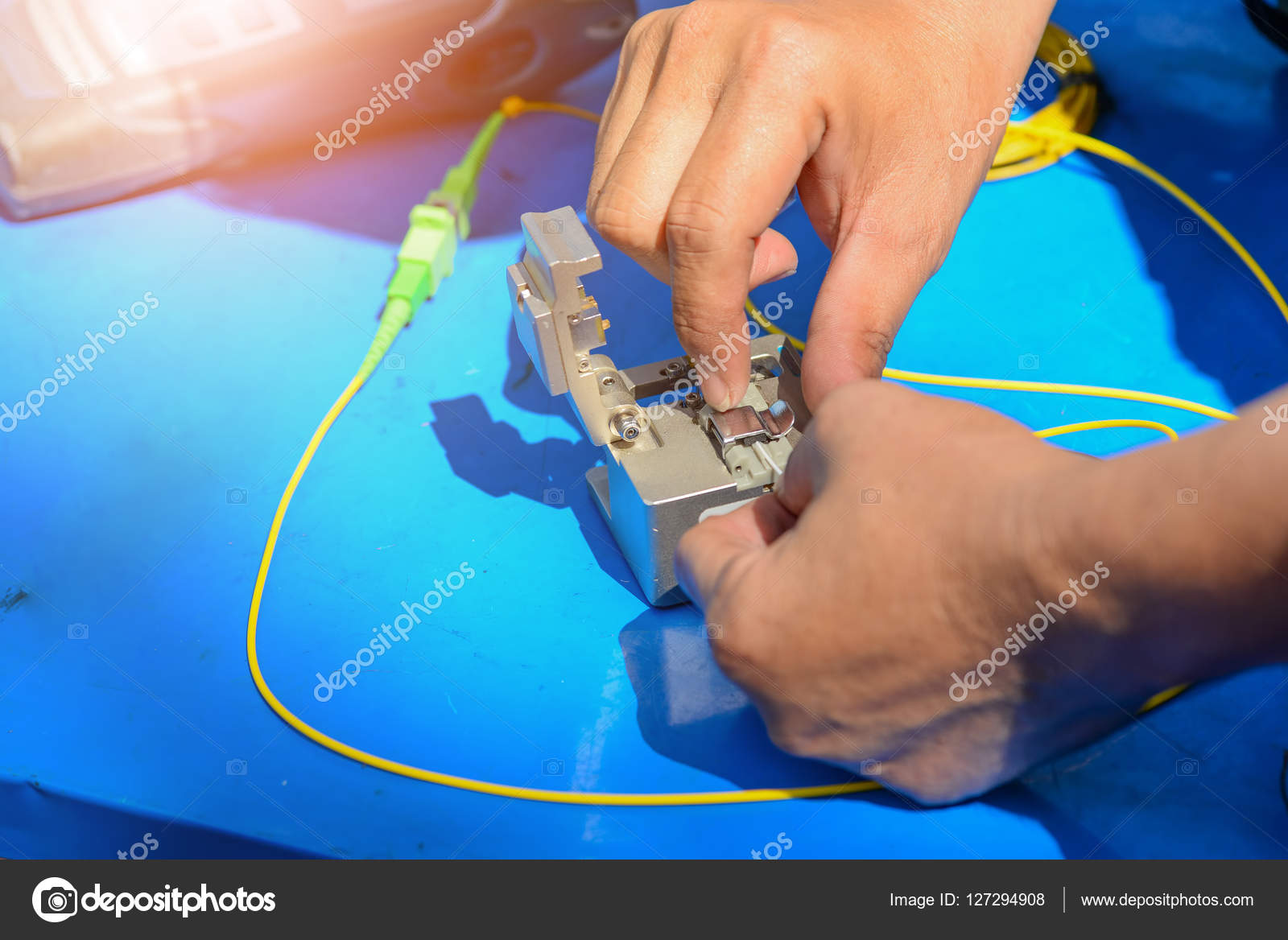 Technician using cleaver cutting optic fiber on blue table with Stock ...