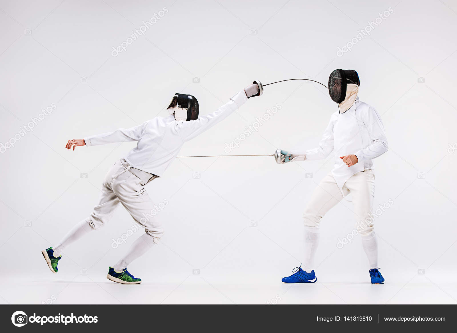 The two men wearing fencing suit practicing with sword against gray ...