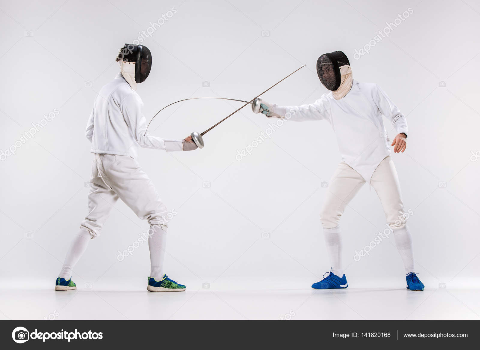 The two men wearing fencing suit practicing with sword against gray ...