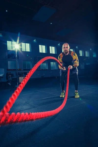Men with battle rope battle ropes exercise in the fitness gym. CrossFit ...