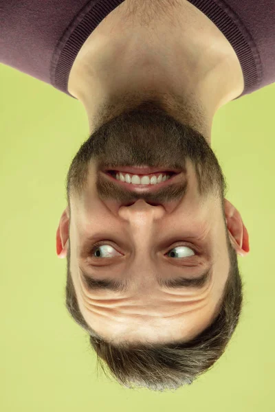 Inverted portrait of caucasian young man on yellow studio background ...