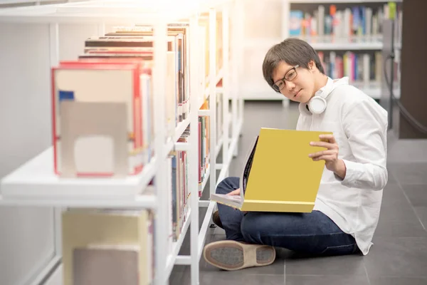 Young Asian man university student reading book in library - Stock ...