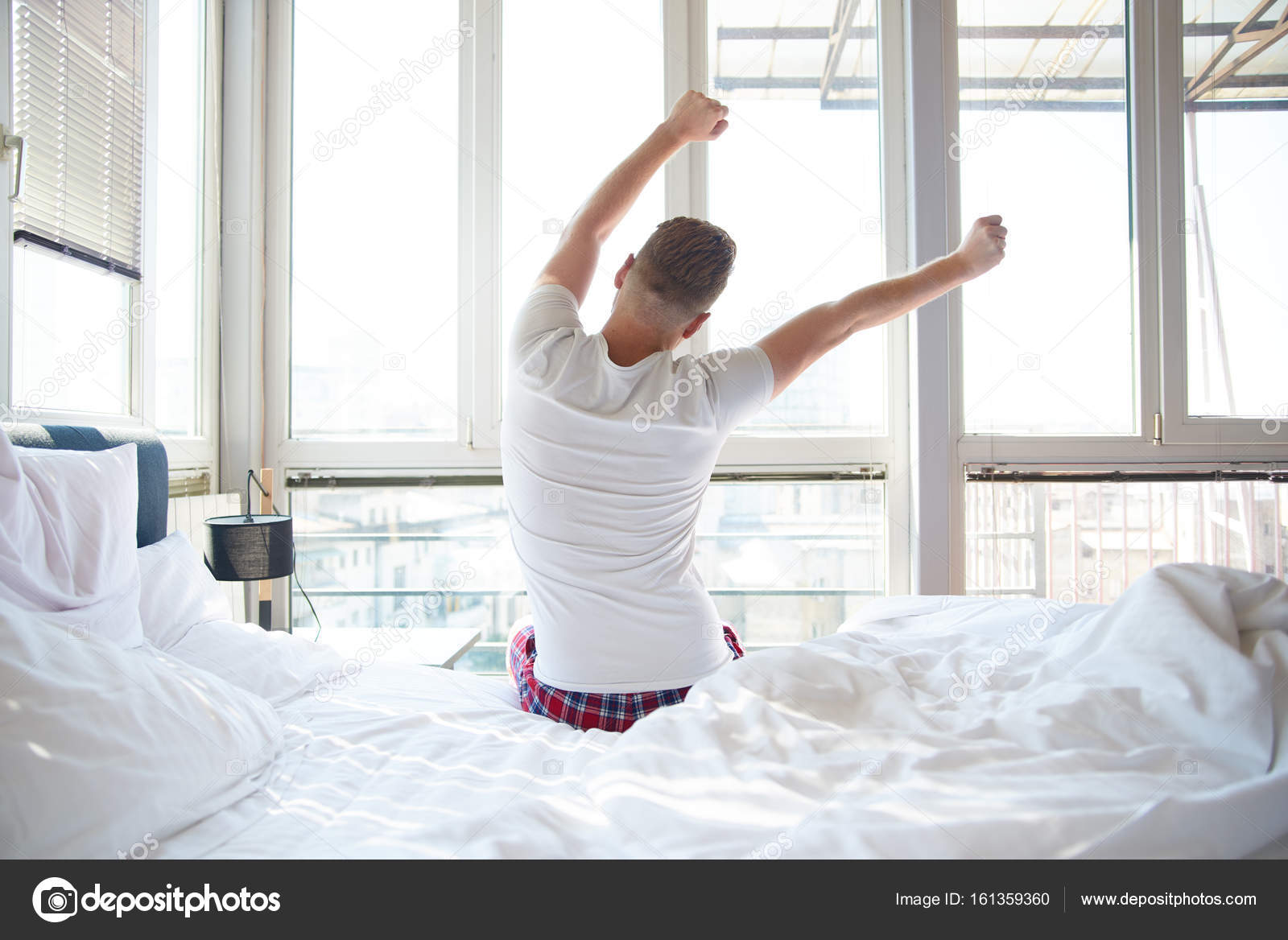 Man stretching in bed Stock Photo by ©nesharm 161359360