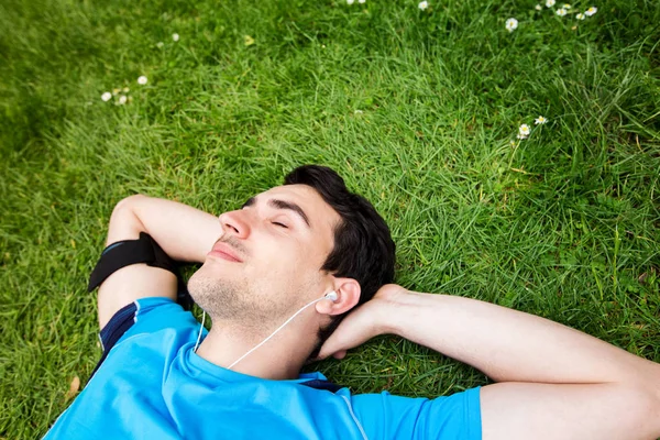Sport fitness man relaxing listening to music after training outdoor in ...