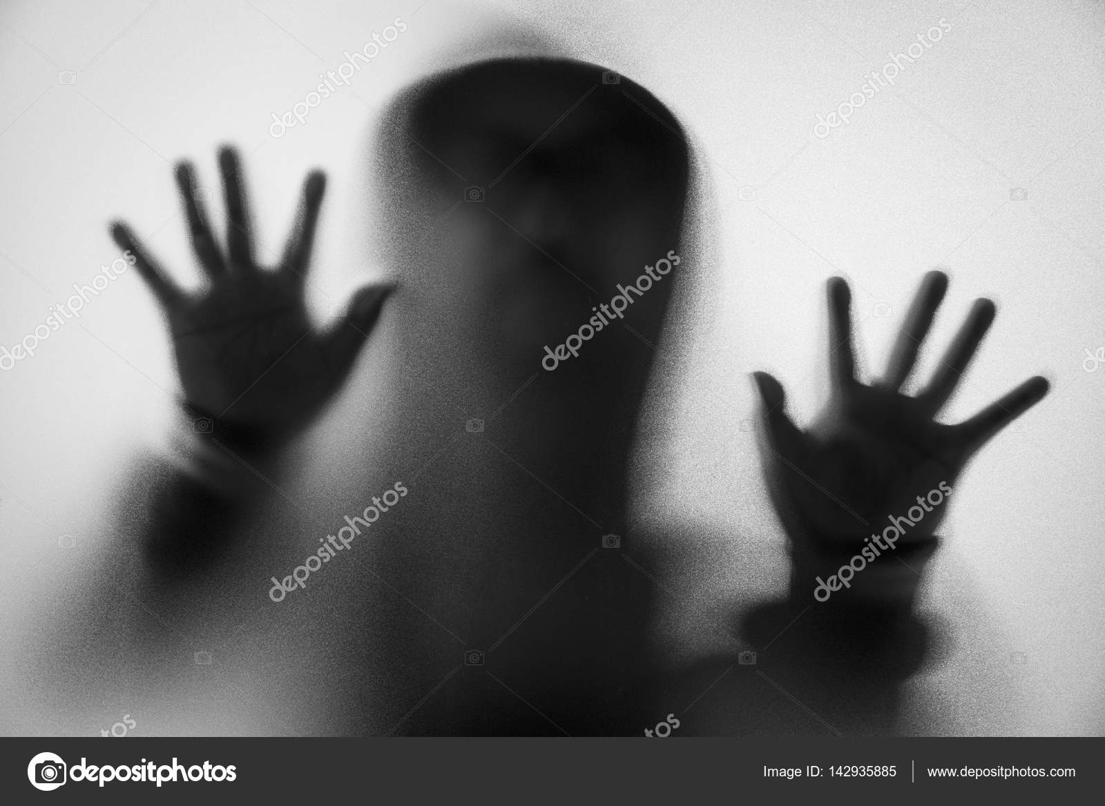 Shadow blur of horror man in jacket with hood.Hands on the glass ...