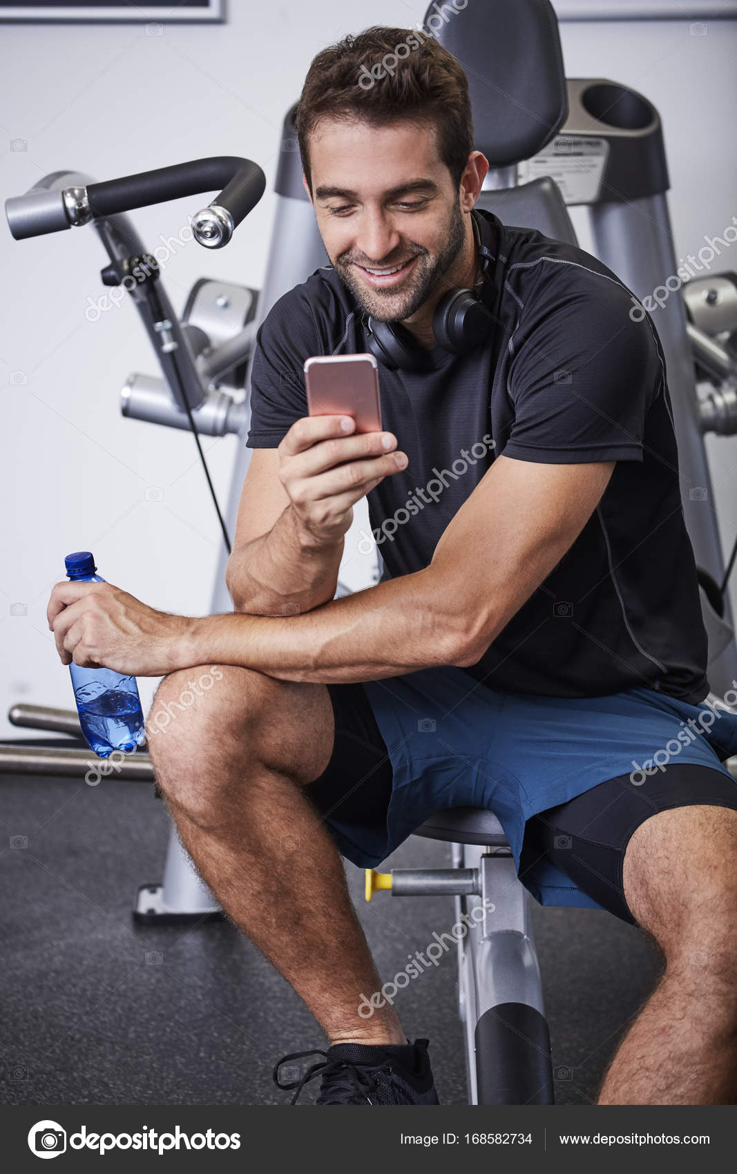 Texting athlete taking a break in gym Stock Photo by ©sanneberg 168582734