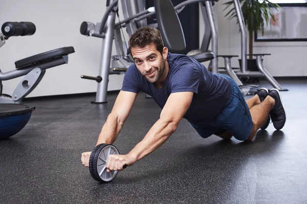 Man performing ab wheel crunches - Stock Image - Everypixel