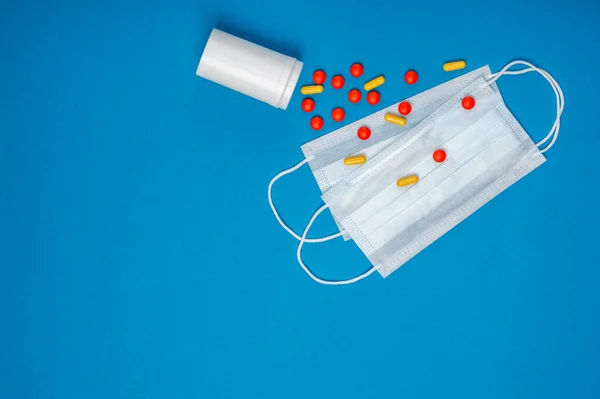 Red and yellow pills from white box and surgical mask with rubber ear ...