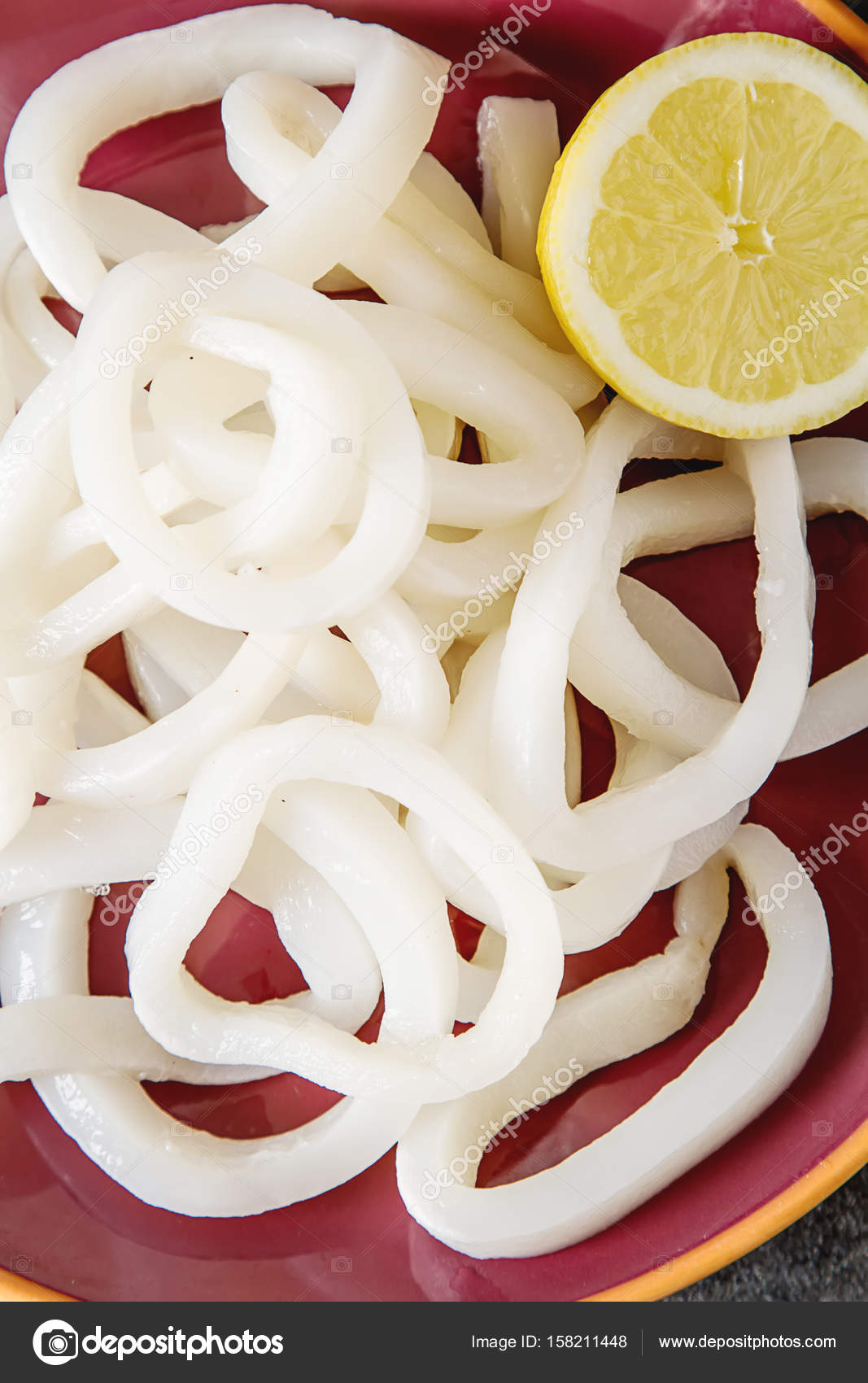 White seafood. Squid rings with lemon on a ceramic plate. Dark b Stock ...