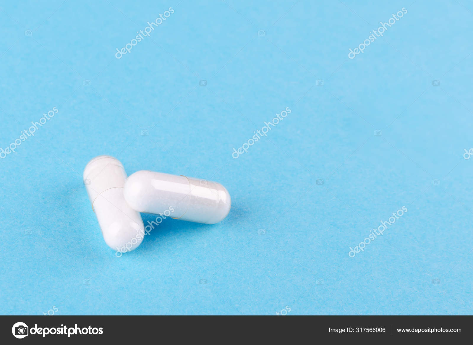 Two white capsules of nutritional supplement on blue background with ...