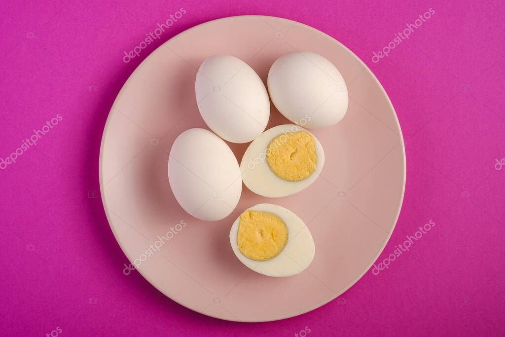 Huevo blanco con huevos cocidos pelados en plato rosa sobre colores ...