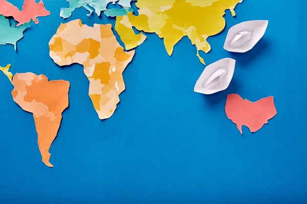 Top view of the white paper boats and international map while cut out ...