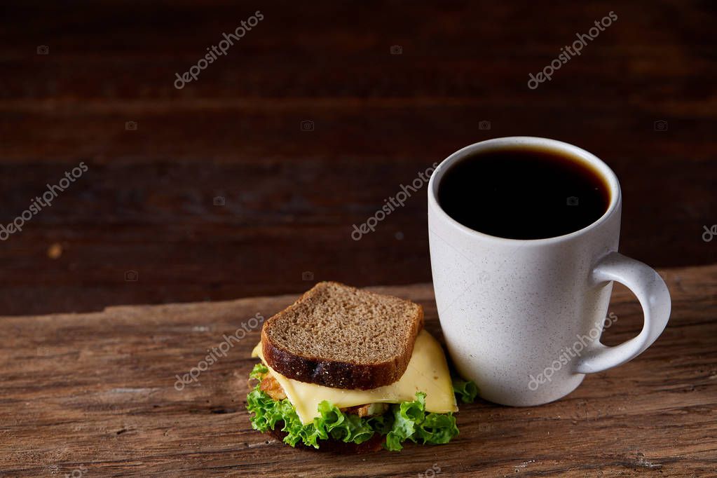Mesa de desayuno con sándwich y café negro sobre fondo rústico de ...