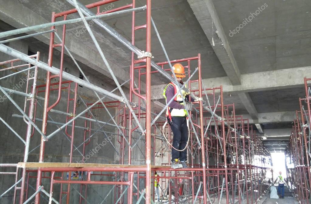 Construction workers wearing safety harness and installing scaffolding ...