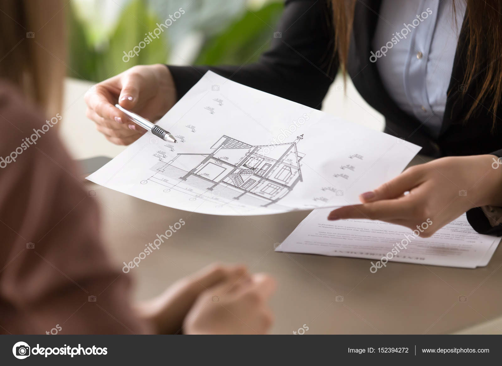 Estate agent showing house plan to client, signing rental agreem ...