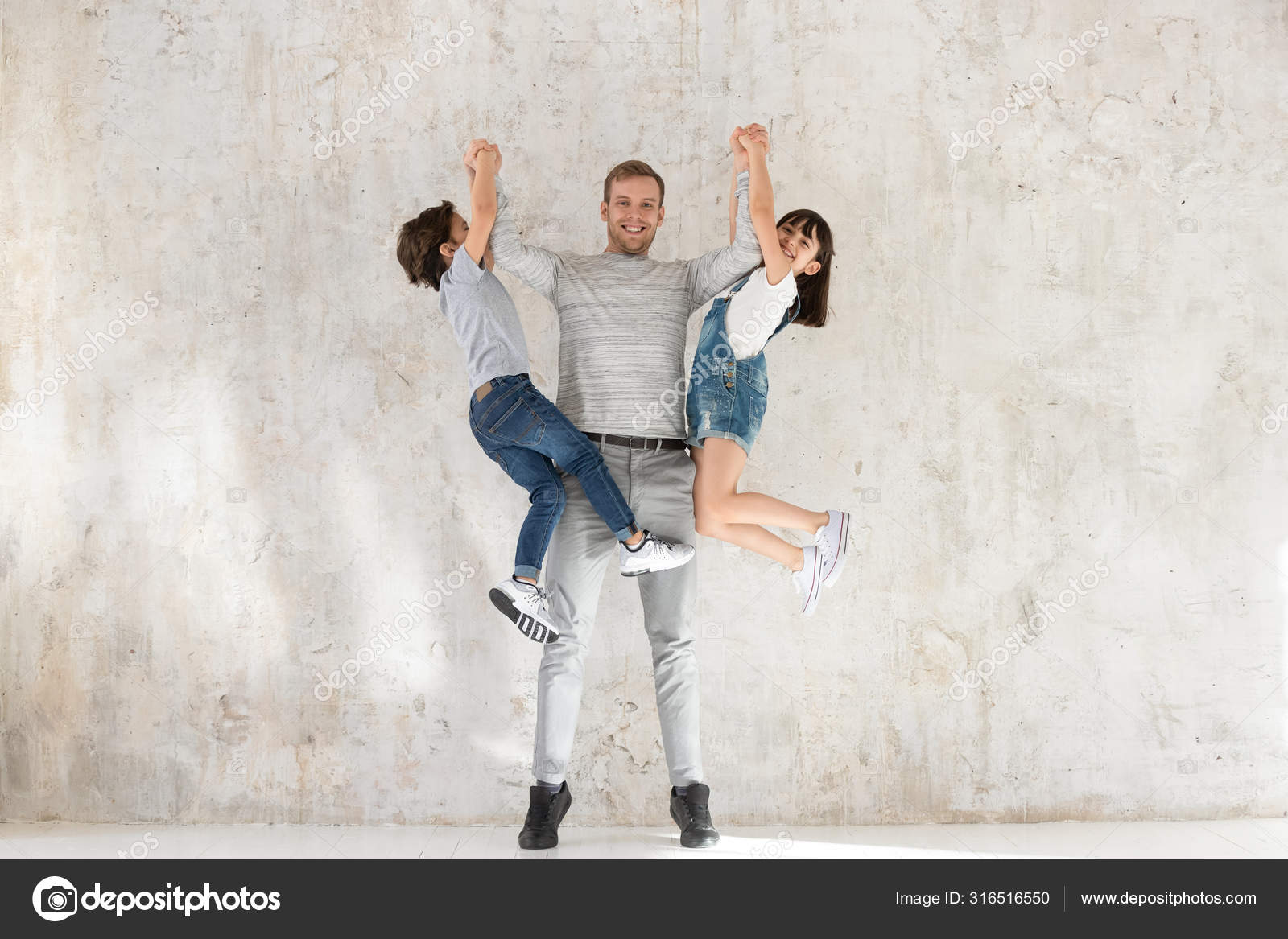 Smiling father holding lifting two little adorable kids on hands ...