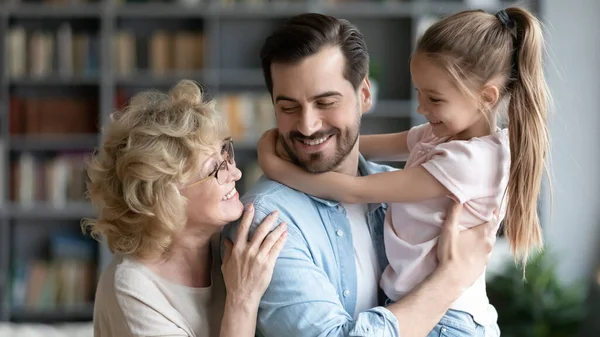 Feliz abrazo de tres generaciones posando juntos en casa 2024