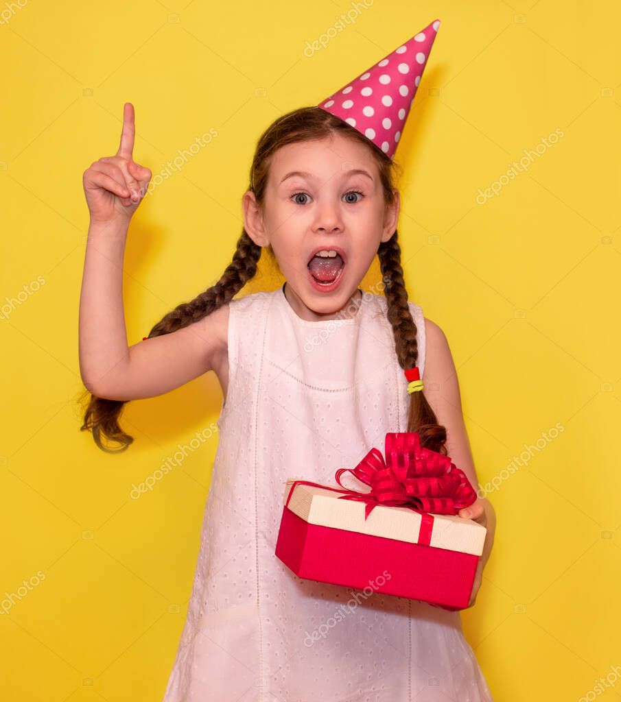 Retrato emocional de una niña pequeña con una gorra en la cabeza y una caja de regalo en las ...