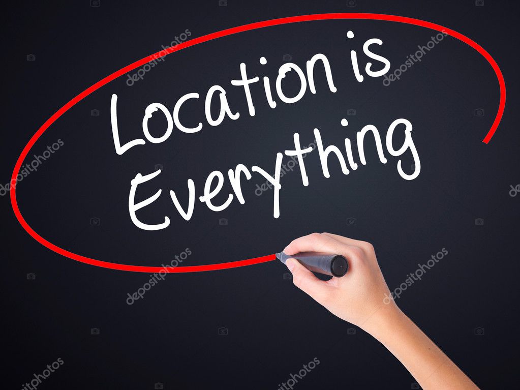 Woman Hand Writing Location is Everything with a marker over tra ...