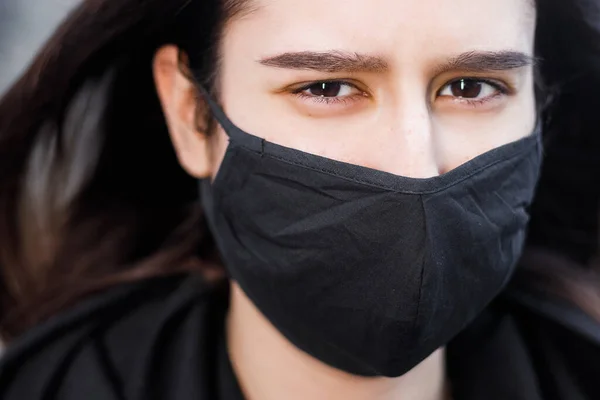 Young woman wearing face mask. Handsome woman in black hoodie wear ...