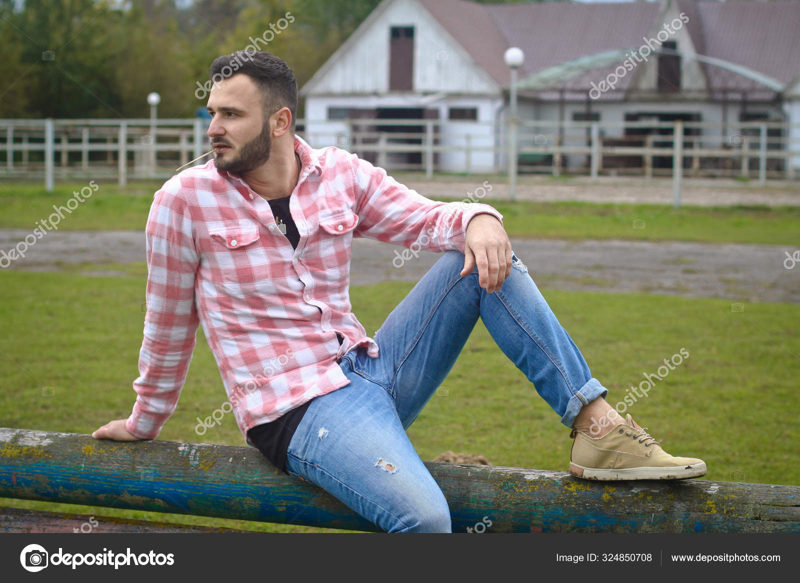 Young handsome guy Cowboy. male farmer is sitting on his fence on his ...