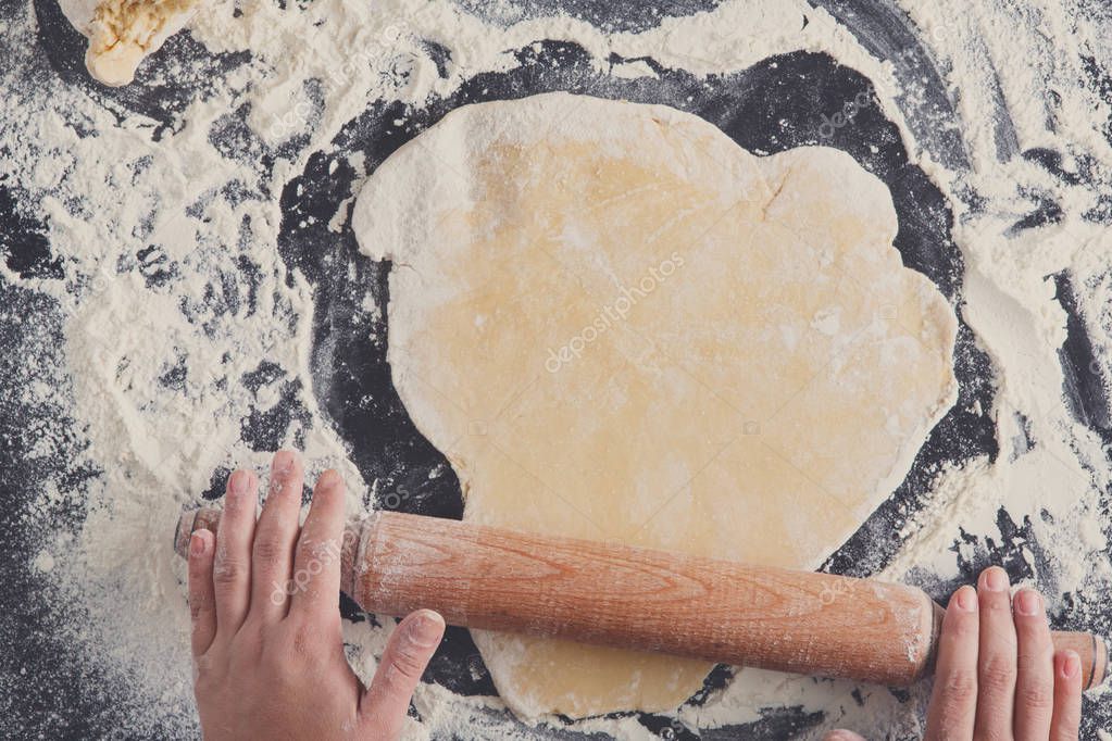 Concepto de hornear. Manos arriba ver rollo de masa sobre fondo negro. 2023