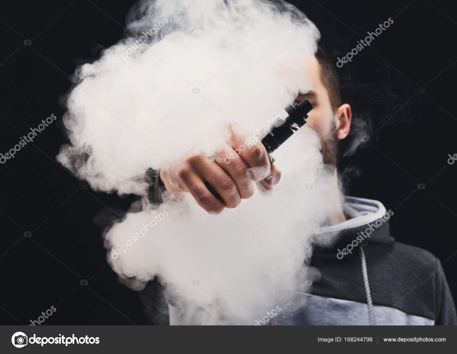 Young man vaping e-cigarette with smoke on black — Stock Photo © Milkos ...