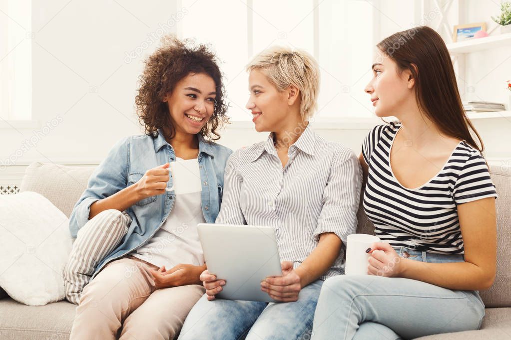 Tres amigas felices usando tableta y tomando café 2023