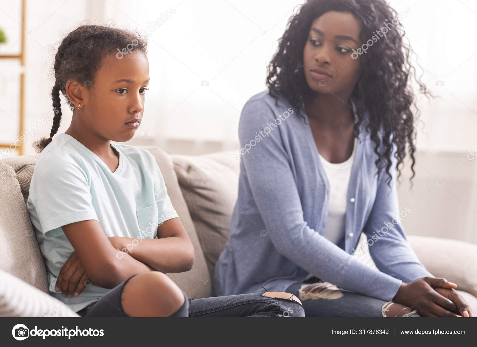 Disappointed black mother looking at her little daughter with reproach ...