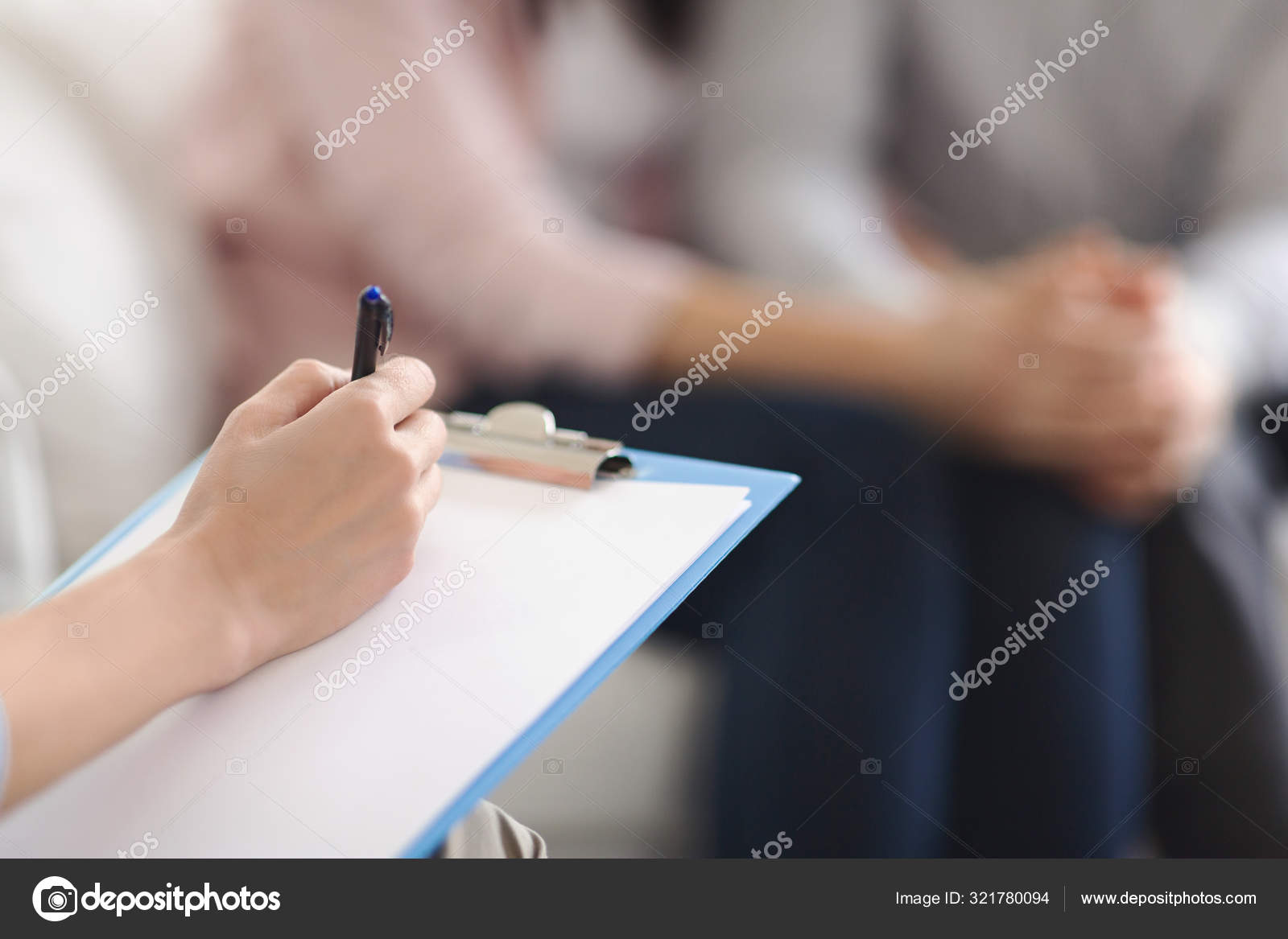 Psychologist writing in blank notepad at family counseling session ...
