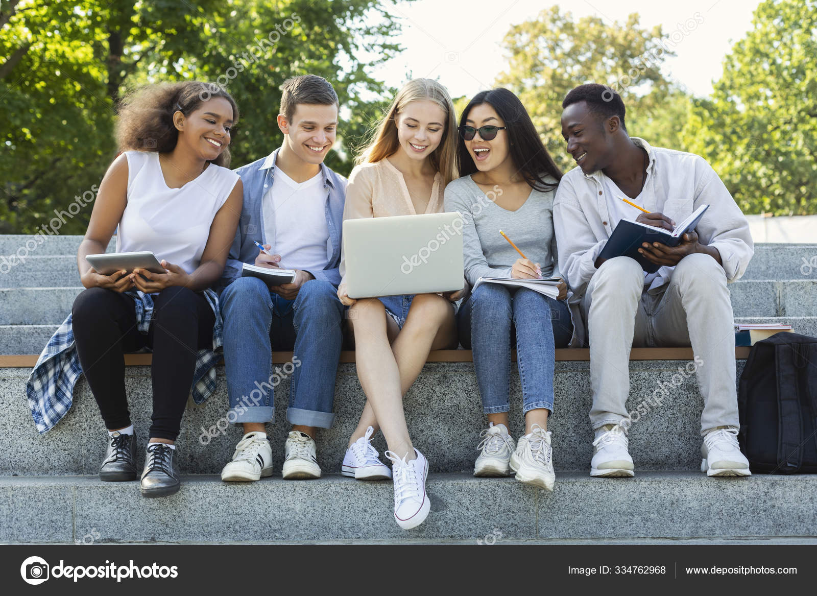 Group of international students using laptop at park Stock Photo by ...