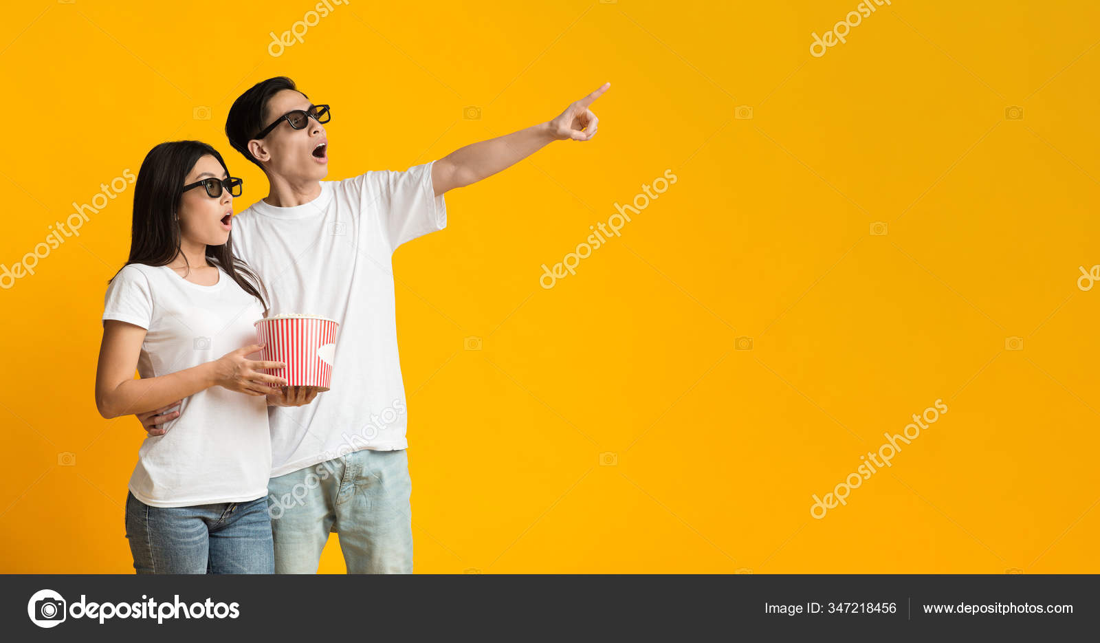 Shocked asian couple in 3d glasses watching movie with popcorn — Stock Photo © Milkos #347218456