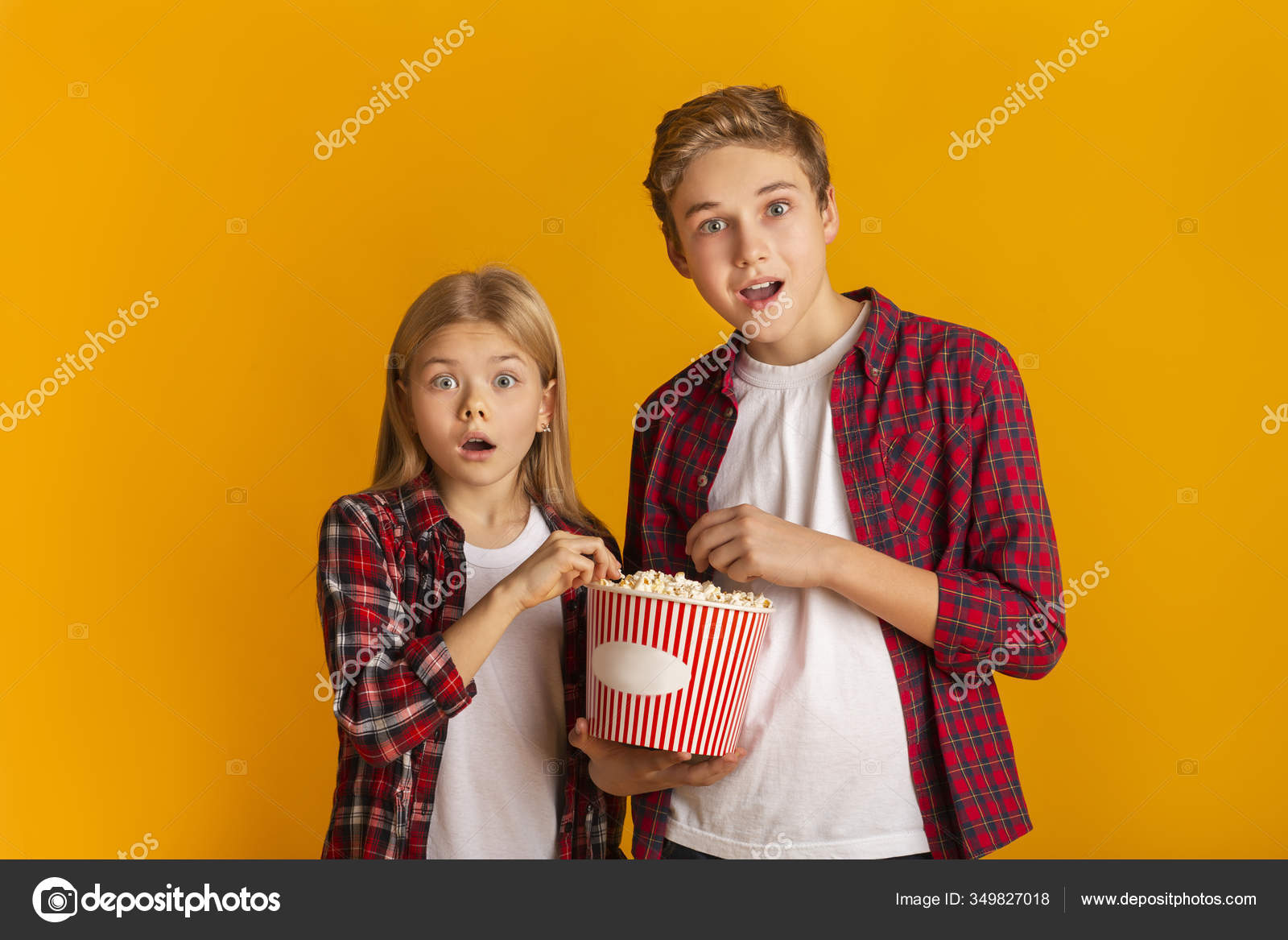 Shocked siblings eating popcorn and opening mouth in amazement Stock ...