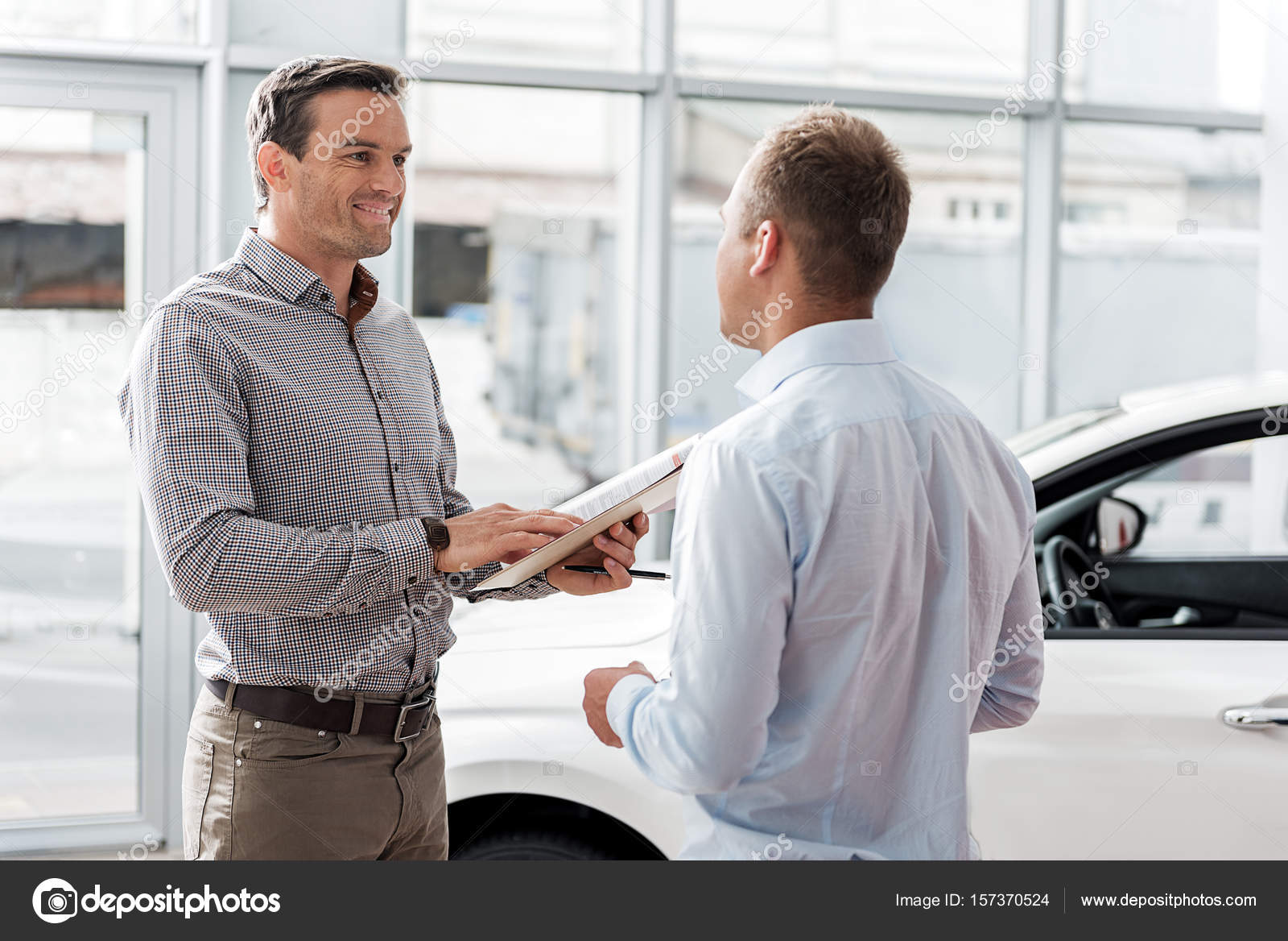 Outgoing man telling with worker in car dealership Stock Photo by ...