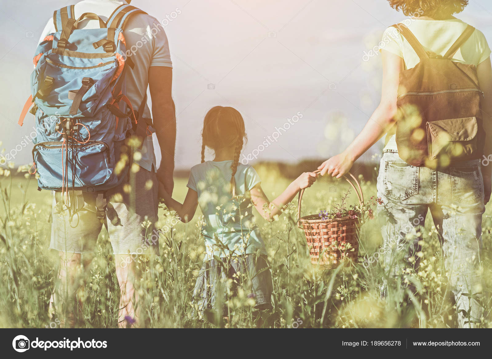 Friendly parents and daughter walking on meadow Stock Photo by ...
