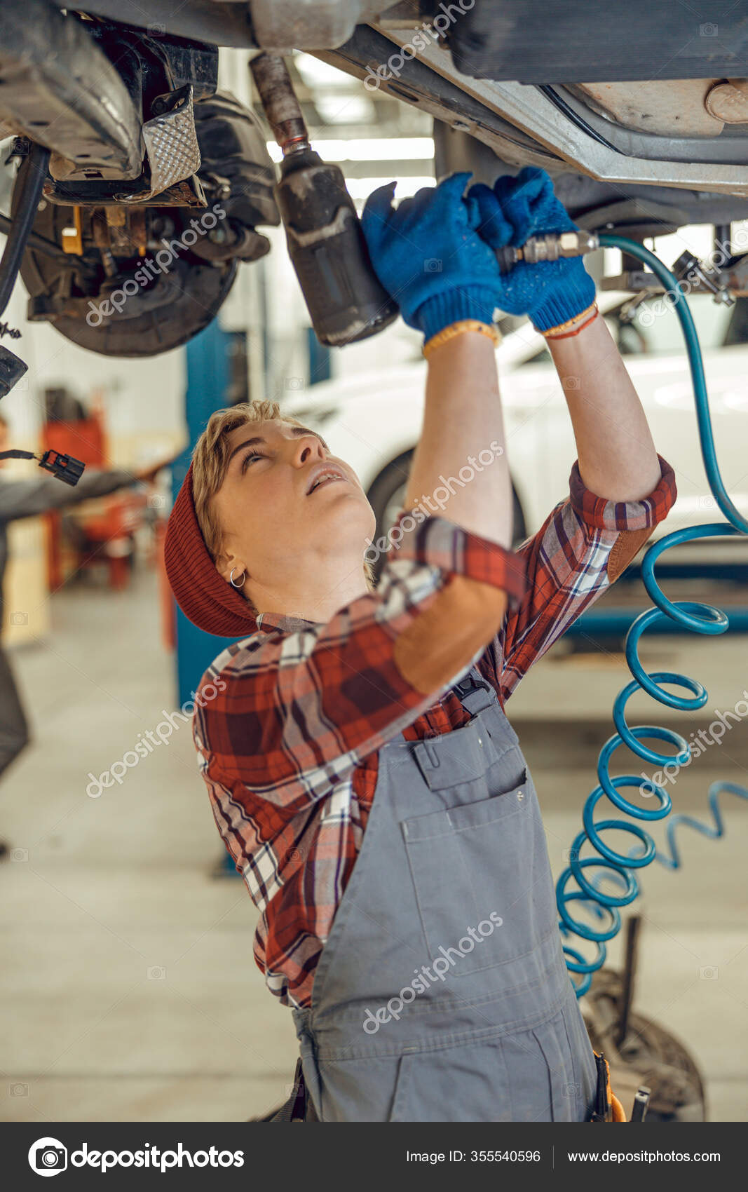 Female mechanic standing under a lifted car Stock Photo by ...