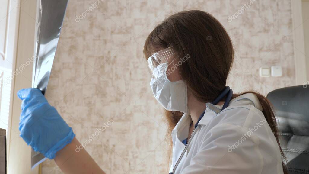 Una doctora en un consultorio examina una radiografía del paciente en el hospital. médico ...
