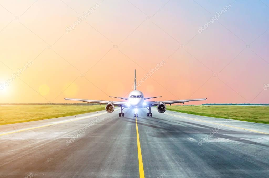 Aircraft taxiing on the runway at the airport at dusk with lights on ...