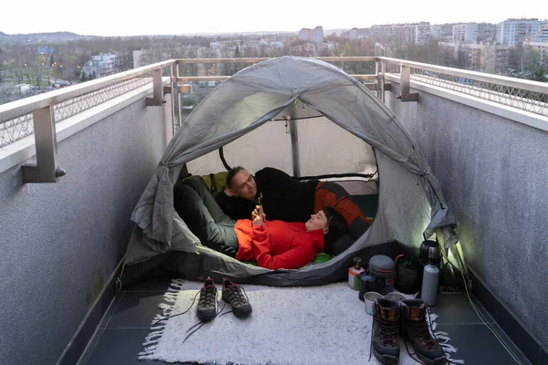 Couple is chilling in touristic tent on the balcony of their apartment ...